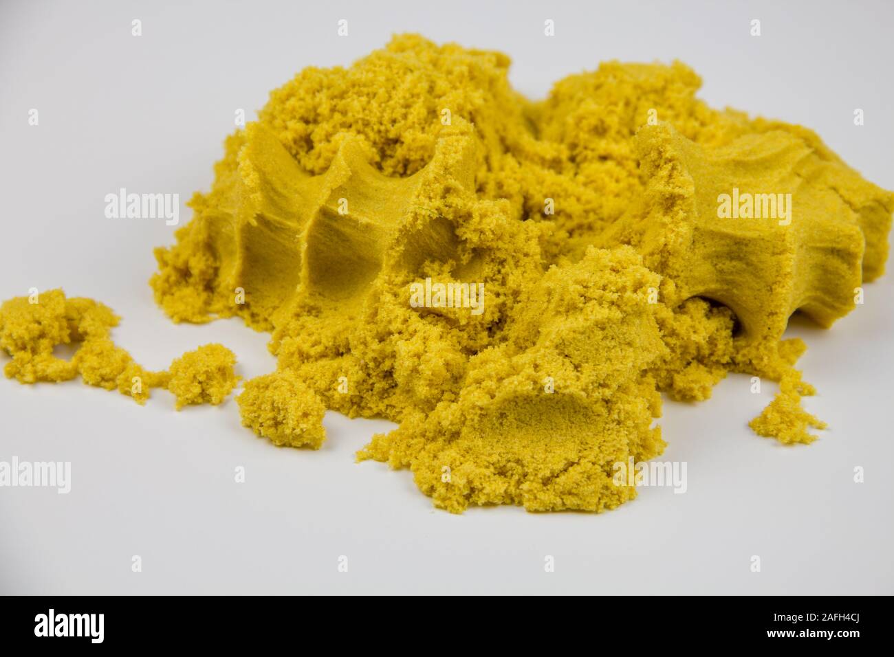 yellow kinetic sand scattered on a white table Stock Photo - Alamy