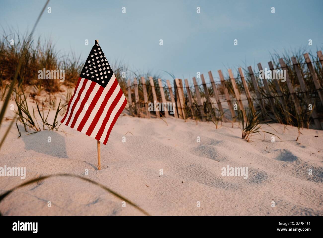 Closeup of the US flag in the sand surrounded by greenery and wooden ...