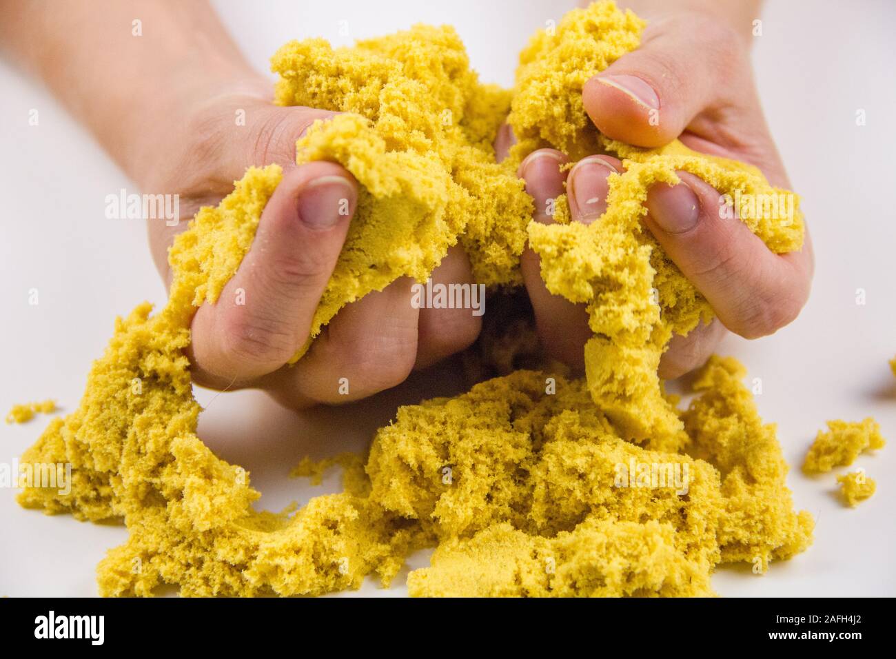 female hands play yellow kinetic sand on a white table Antistress Stock ...