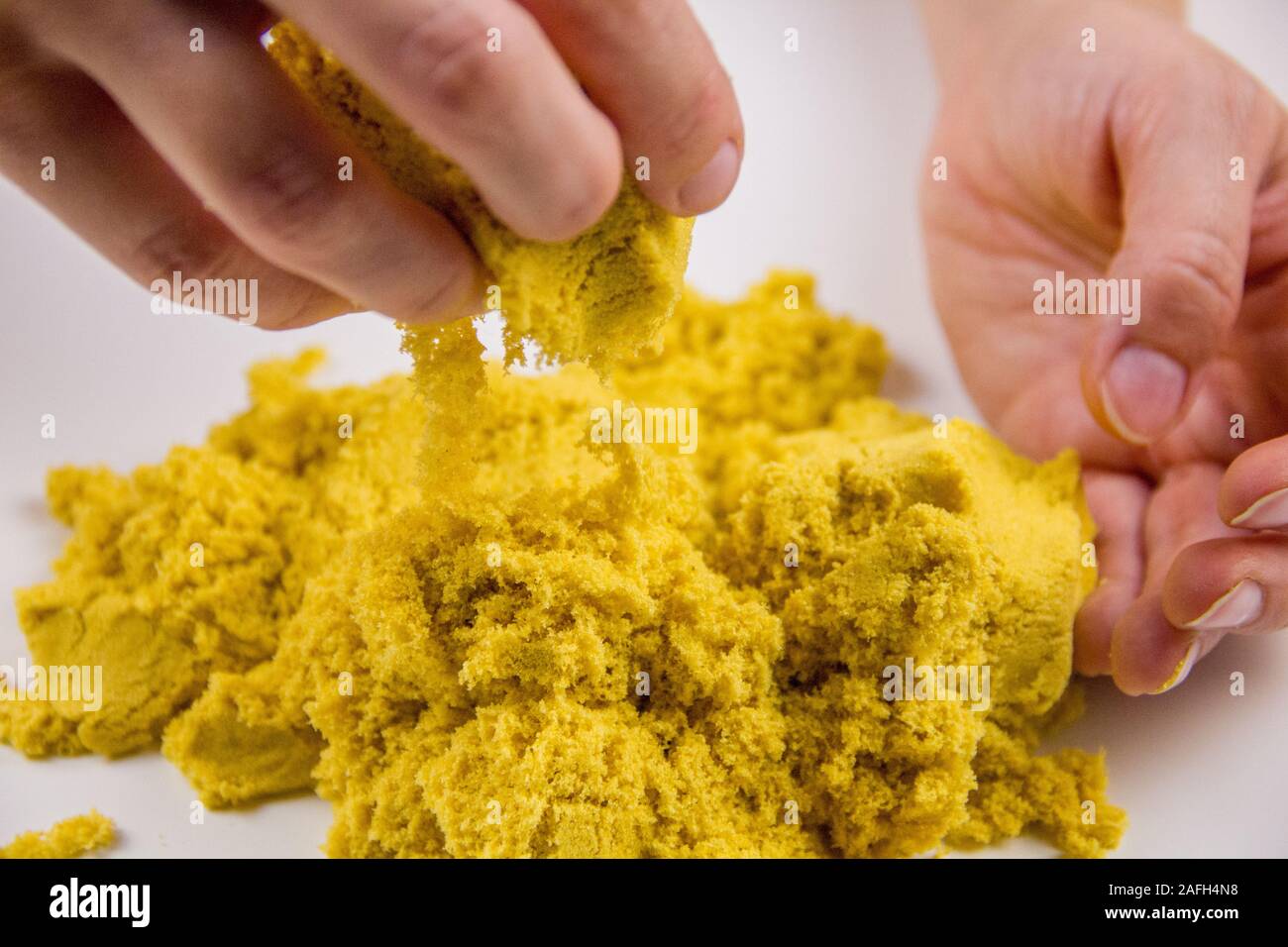 female hands play yellow kinetic sand on a white table Antistress Stock ...