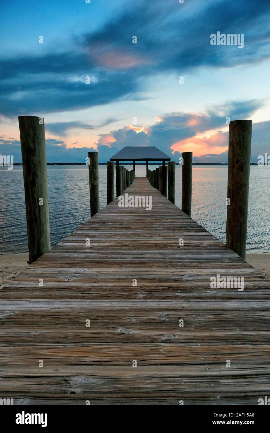 Wooden bridge in the sea under a cloudy sky during sunset - a cool ...