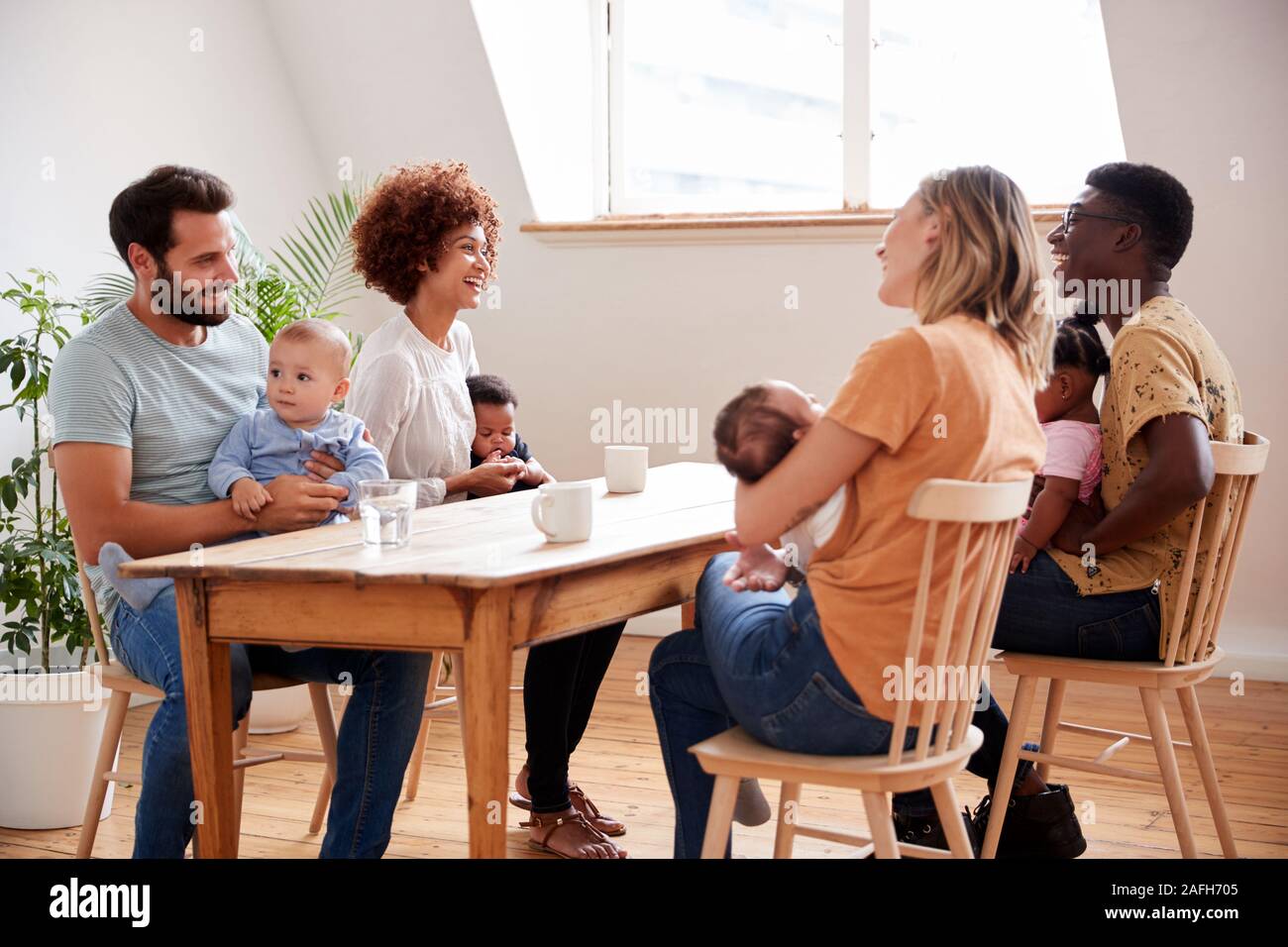 Two Families With Babies Meeting And Talking Around Table On Play Date ...
