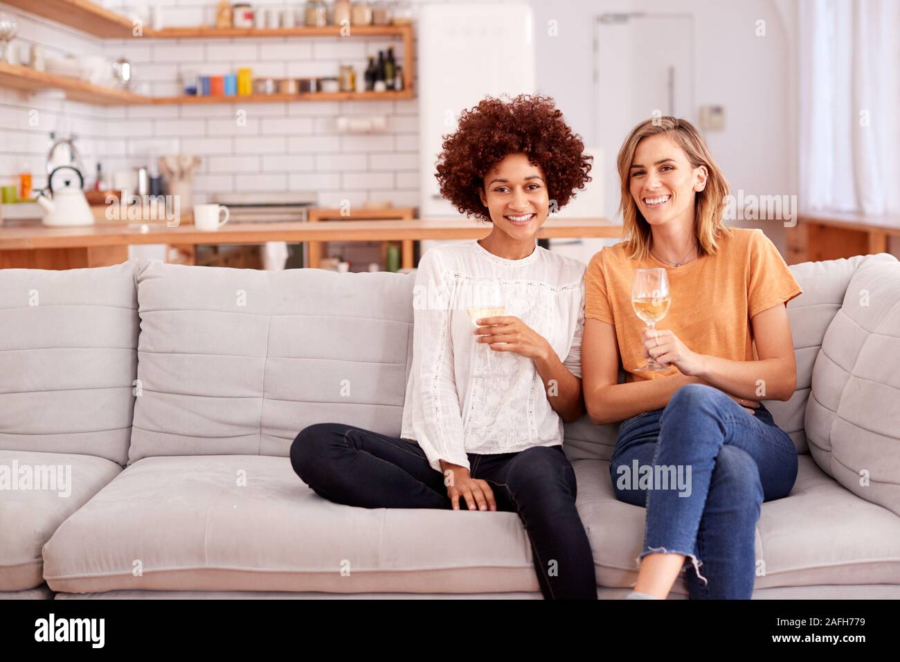 Portrait Of Two Female Friends Relaxing On Sofa At Home With Glass Of ...