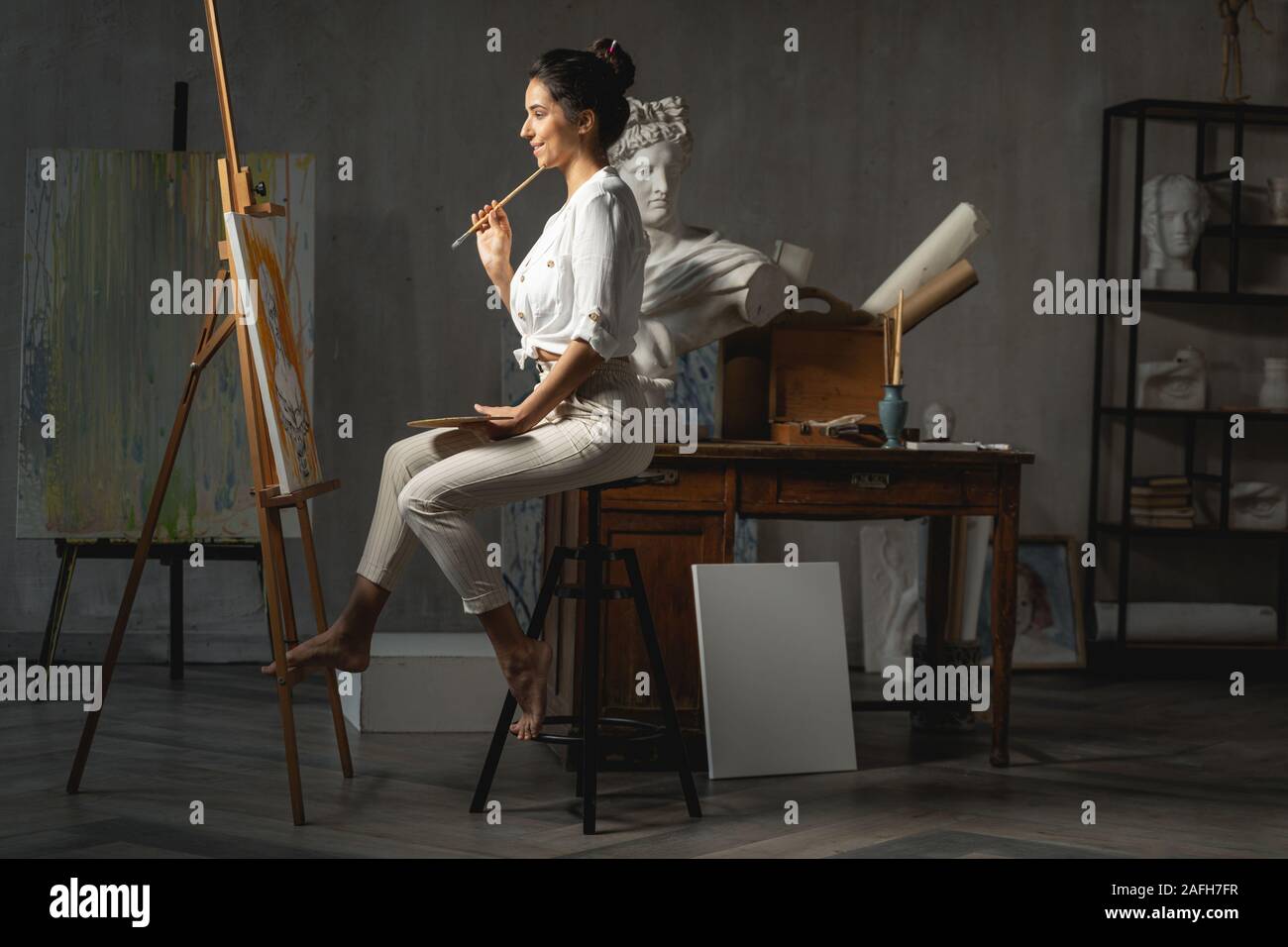 Smiling young female artist thinking during working process Stock Photo ...