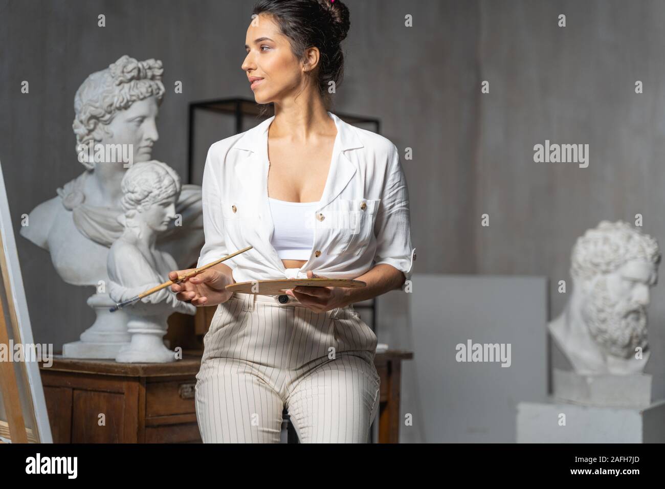 Calm young female artist looking at picture Stock Photo - Alamy