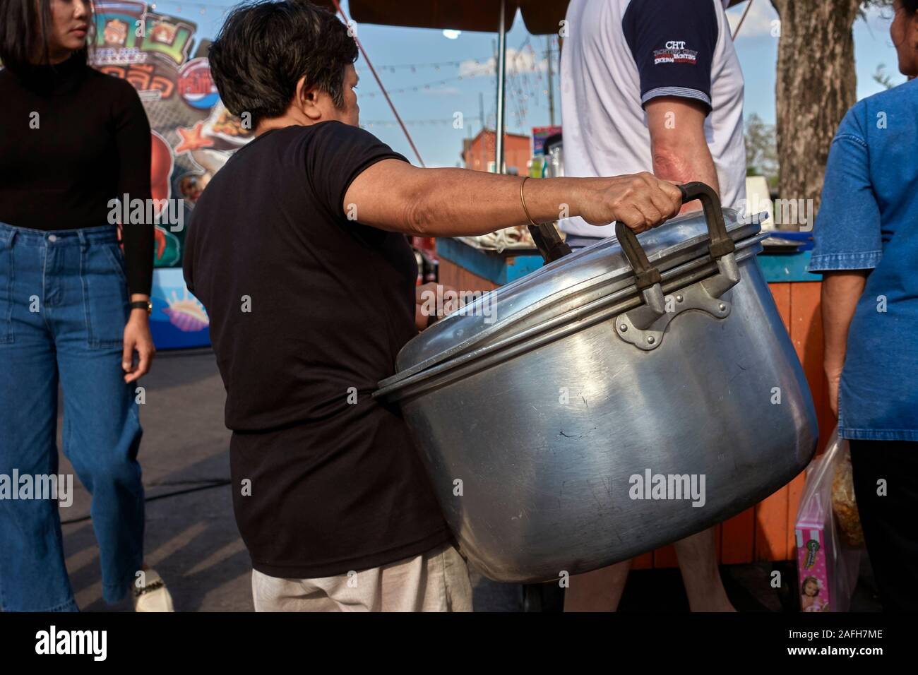 Woman carrying a large metal cooking pot Stock Photo - Alamy