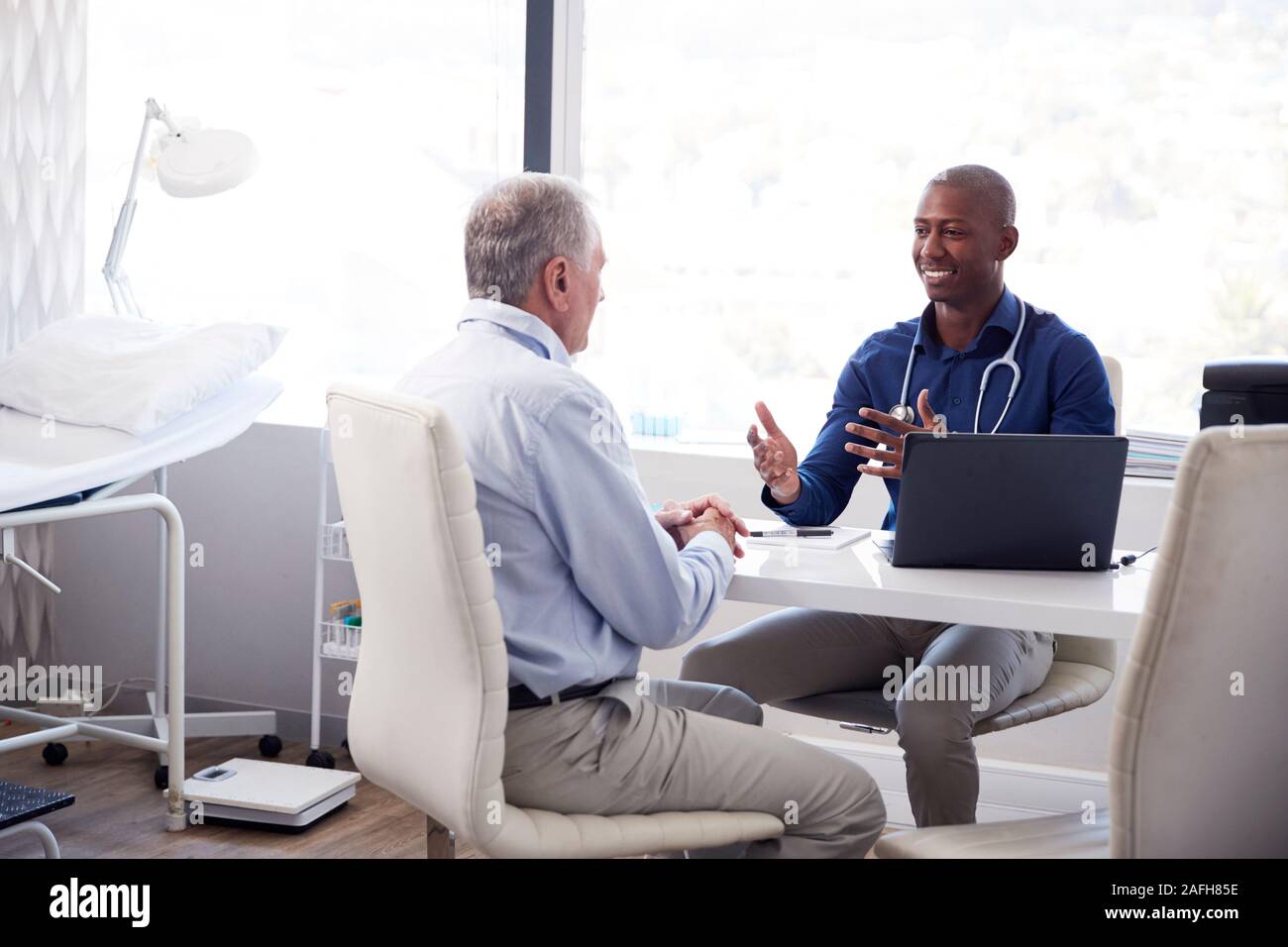 Senior African American male doctor checking patients back using ...