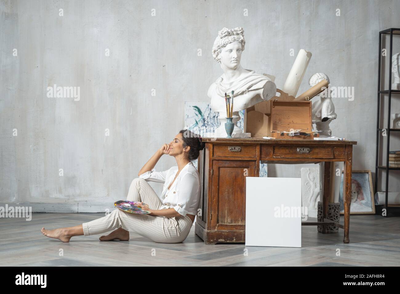 Calm Caucasian female artist is relaxing before painting in art room ...
