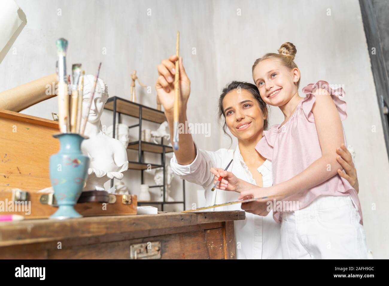 Caucasian artist explaining little girl how to hold paintbrush Stock ...