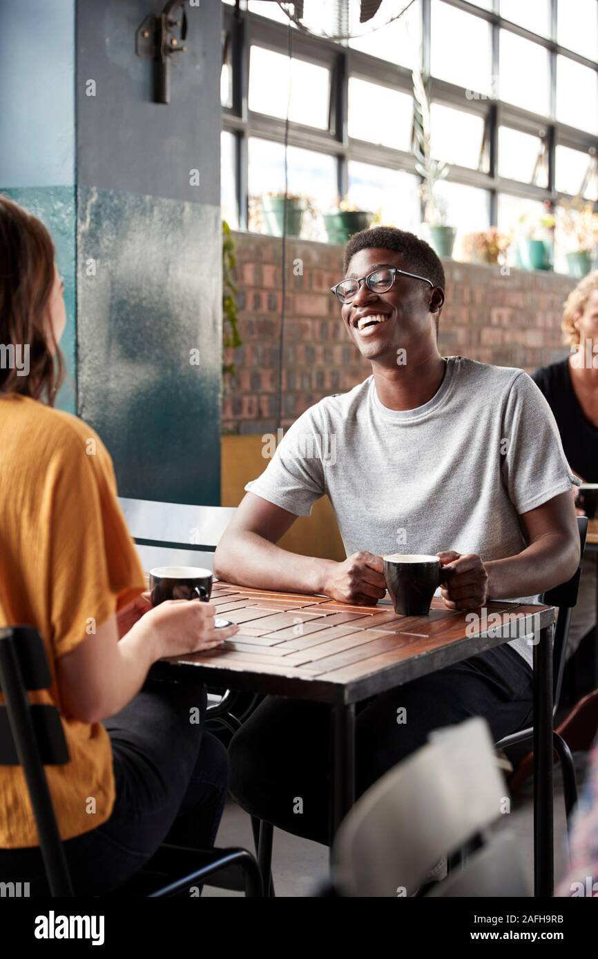 Couple Sitting At Table In Busy Coffee Shop Talking Stock Photo - Alamy