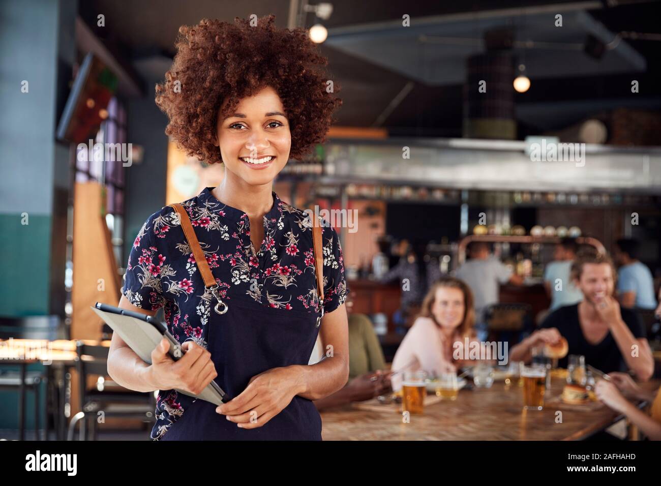 Portrait Of Waitress Holding Menus Serving In Busy Bar Restaurant Stock ...