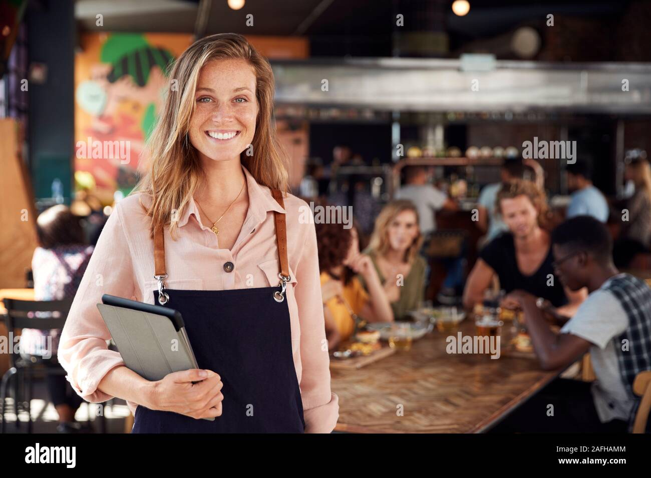 Portrait Of Waitress Holding Menus Serving In Busy Bar Restaurant Stock ...