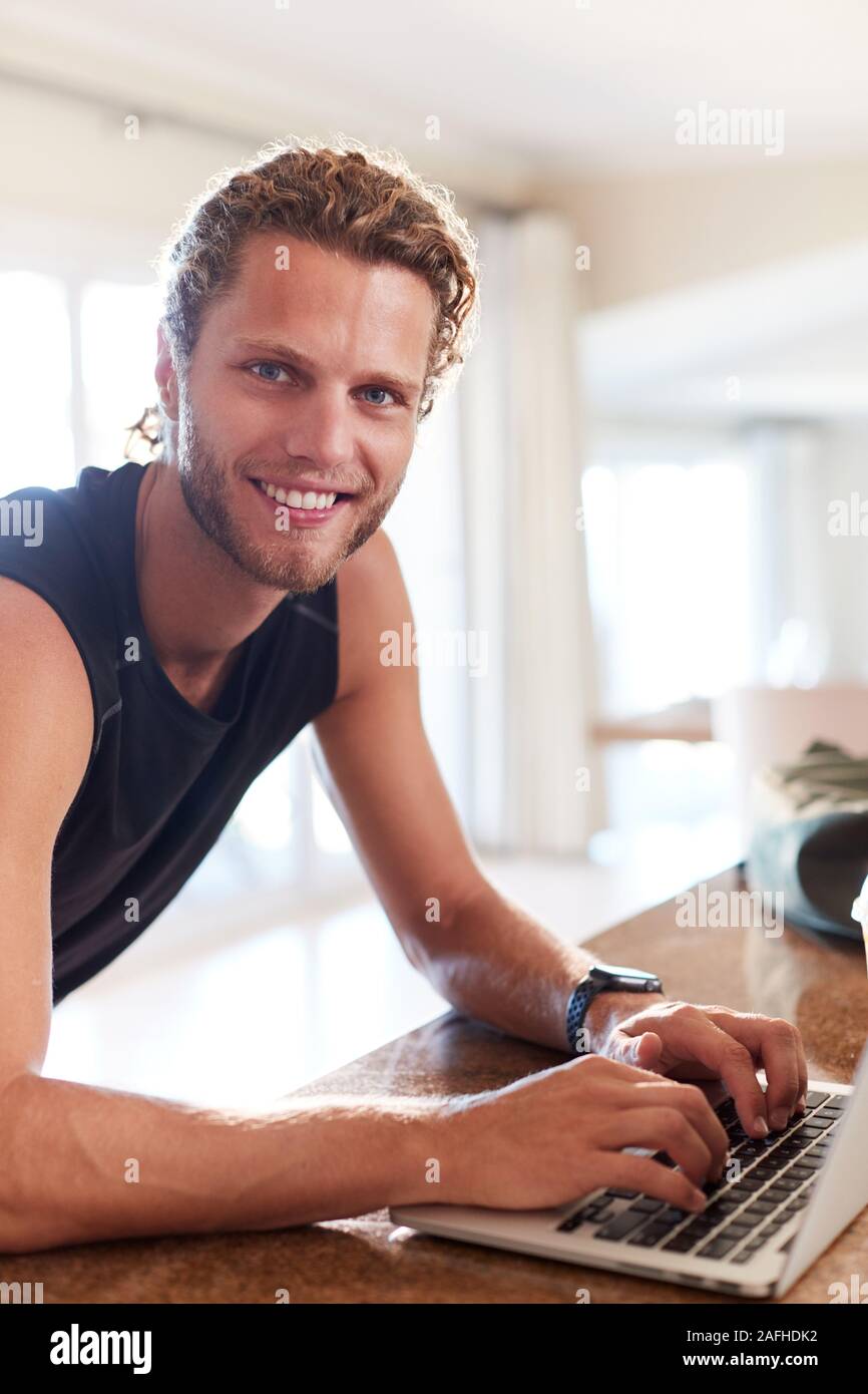 Millennial white man checking fitness app on laptop after a workout ...