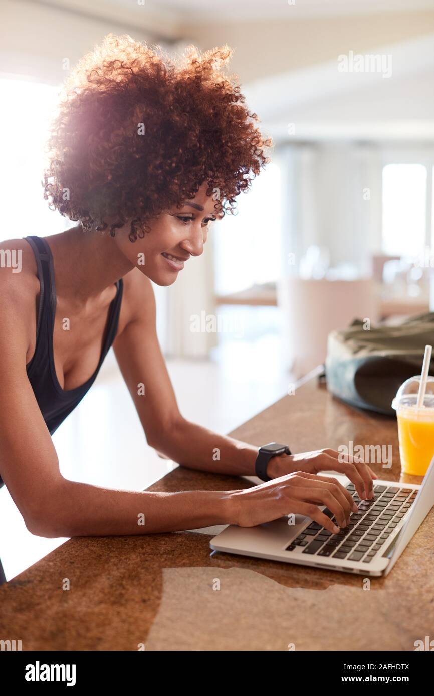 Millennial African American woman using laptop to check fitness data ...