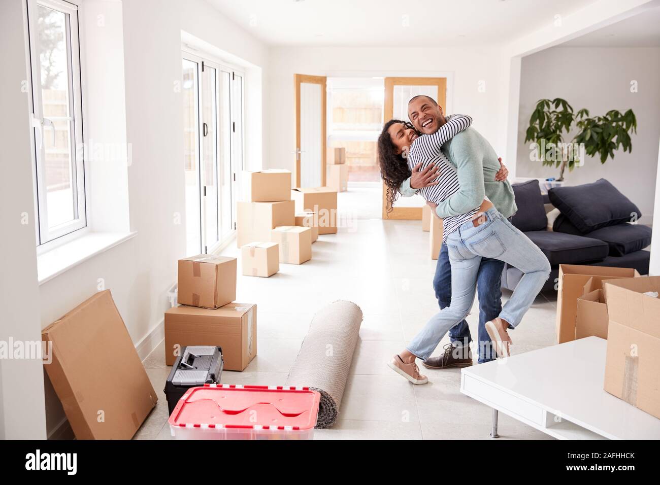 Loving Couple Hugging Surrounded By Boxes In New Home On Moving Day ...