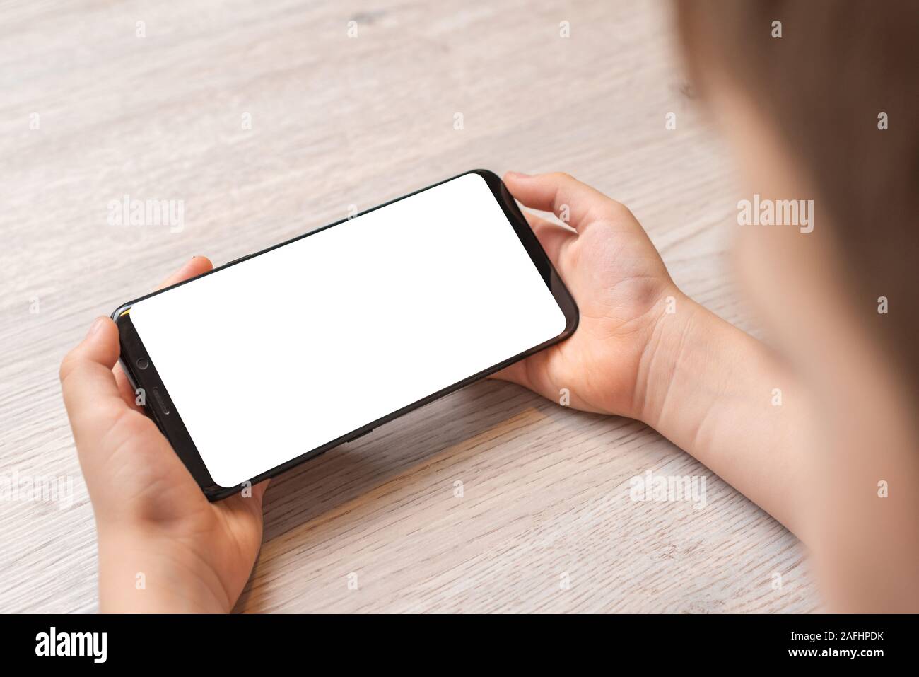 Boy holds mobile phone in horizontal position. Isolated screen for ...