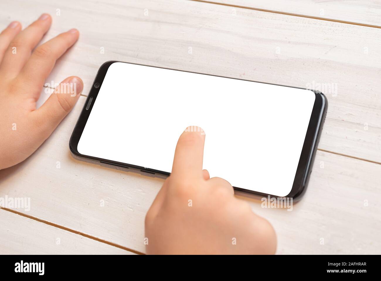 Kid touch smart phone screen on white wooden desk. Isolated screen for ...