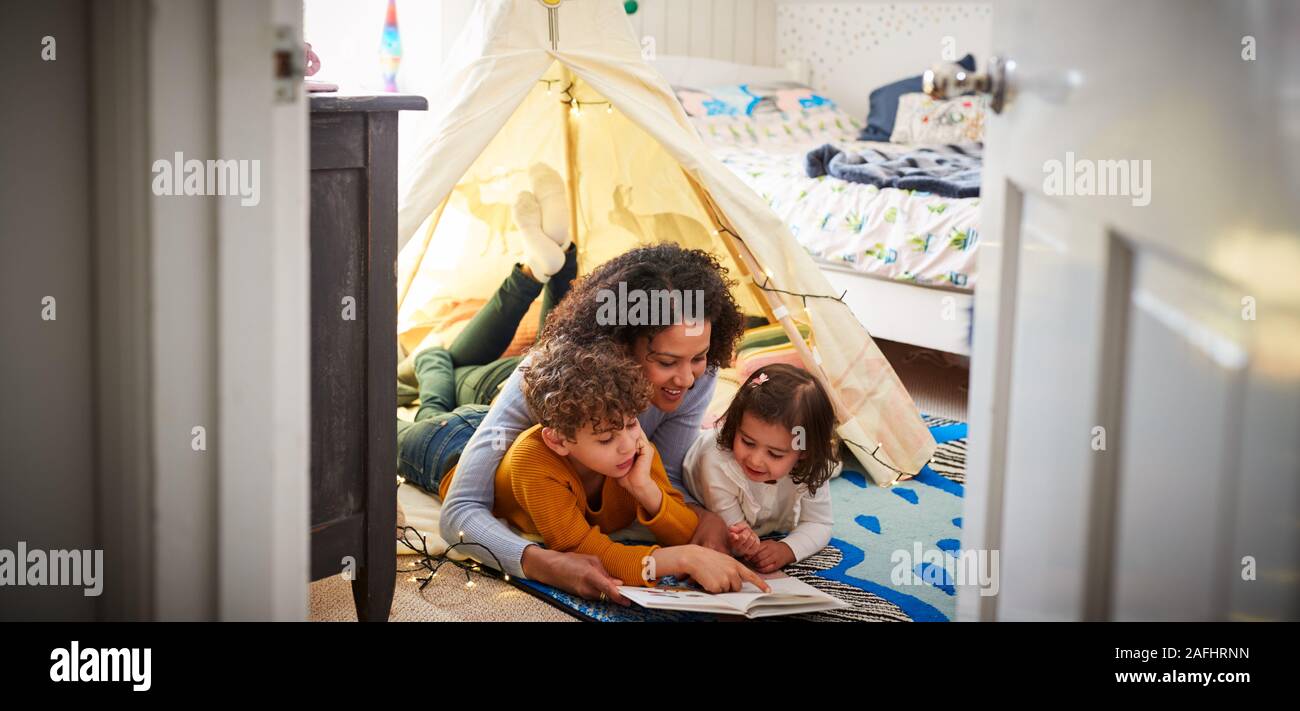 Single Mother Reading With Son And Daughter In Den In Bedroom At Home ...