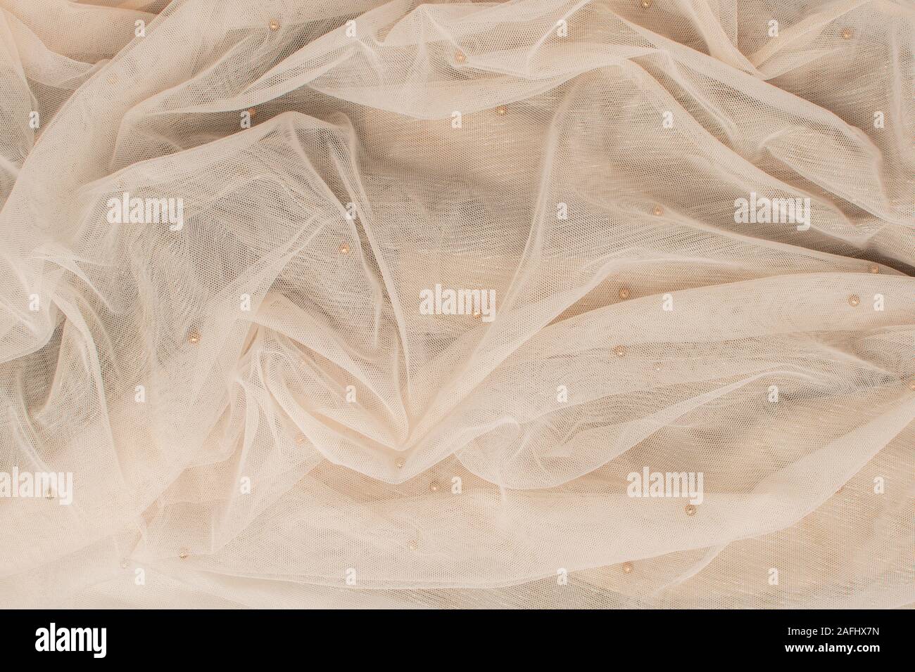 background from beige crumpled tulle with small beads. Abstract ...