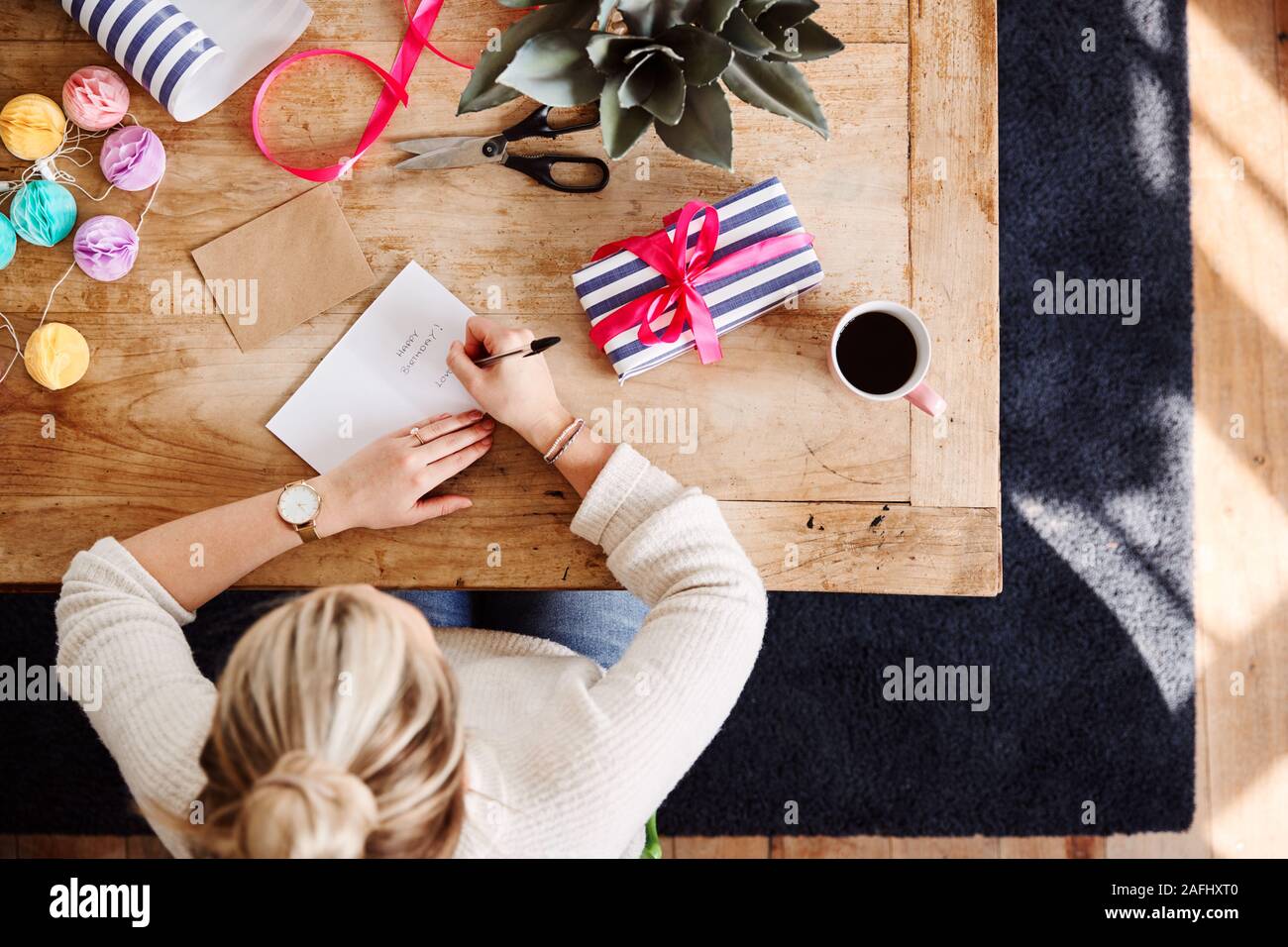 Overhead Shot Looking Down On Woman At Home Writing In Birthday Card ...