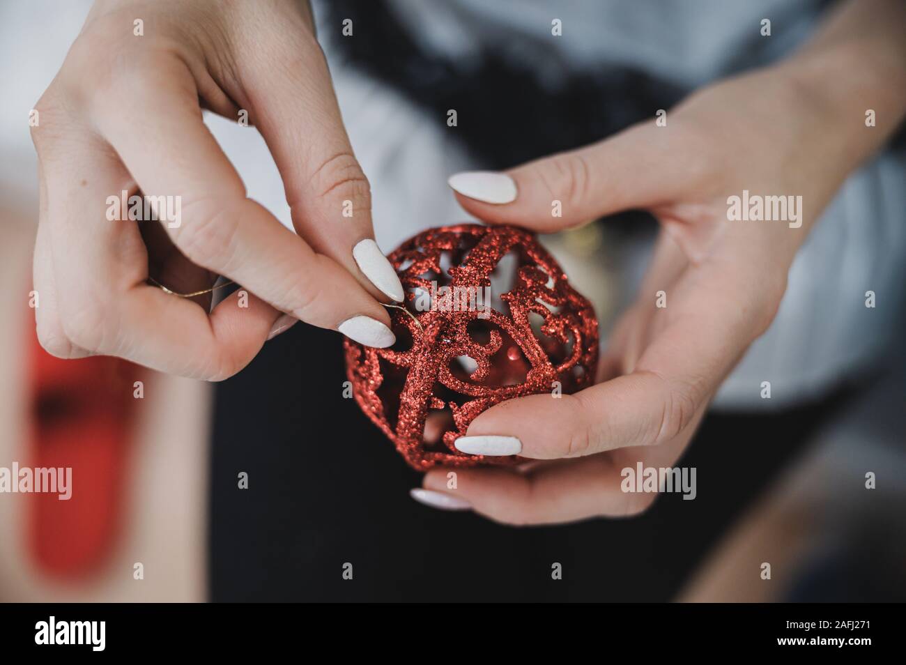 Top view of a woman attaching golden string to red Christmas ornament ...