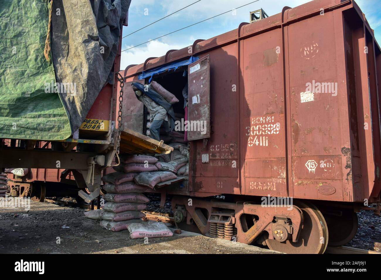 An Indian labourer unloads a cement bag from freight trains at the ...