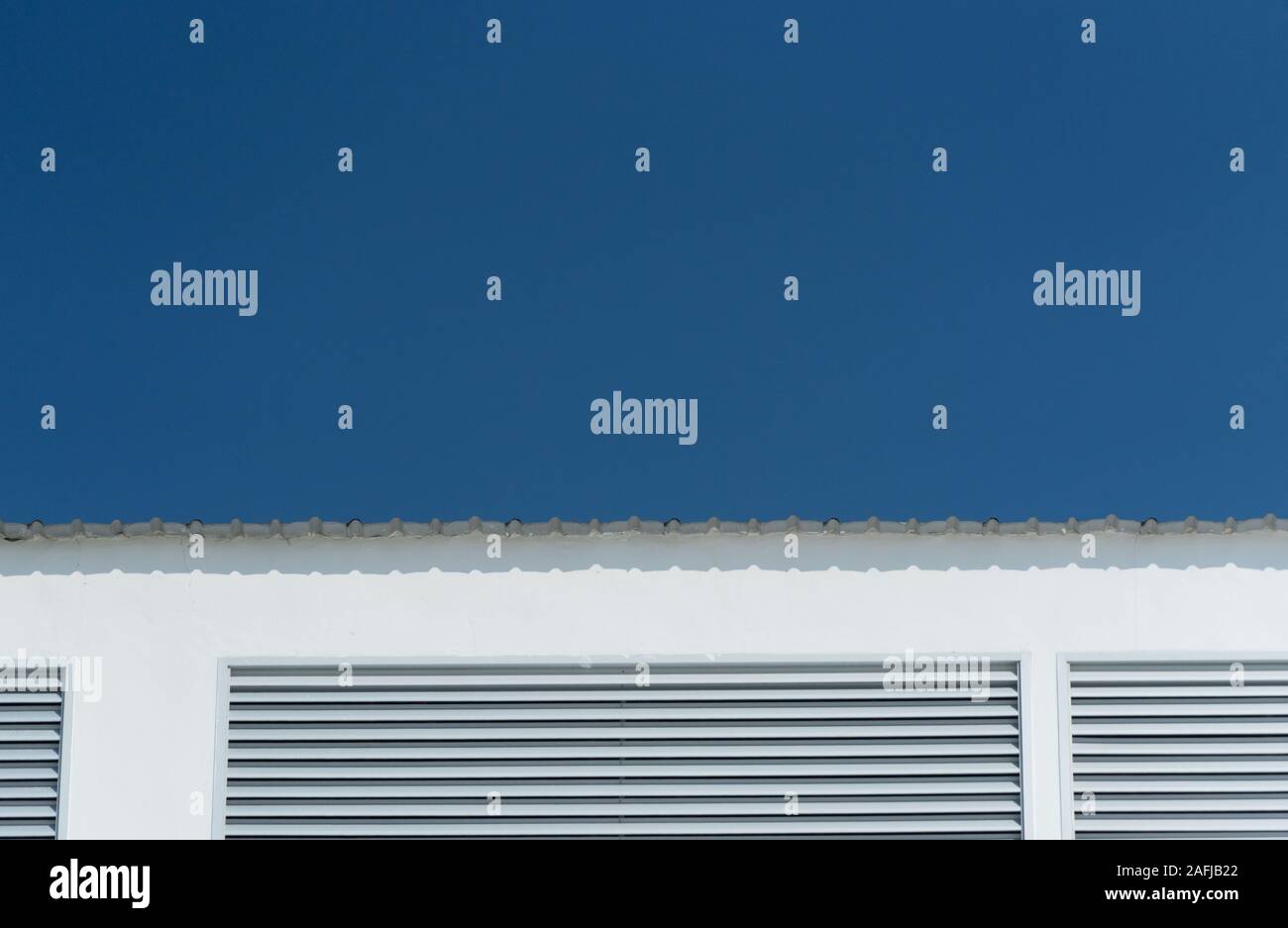simple part of white cement building with metal roof with blue sky ...