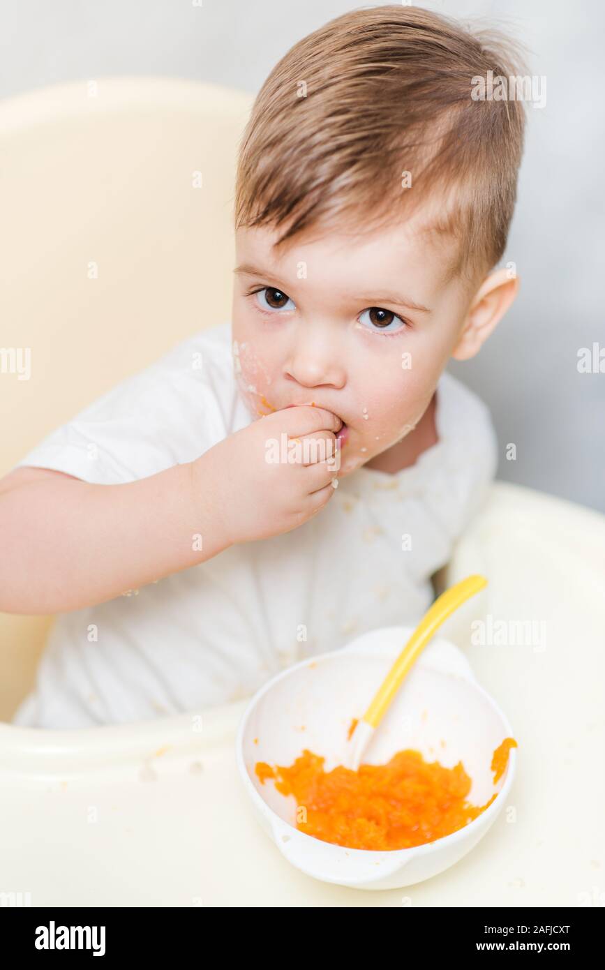 happy baby eating a pumpkin with a small spoon himself Stock Photo - Alamy