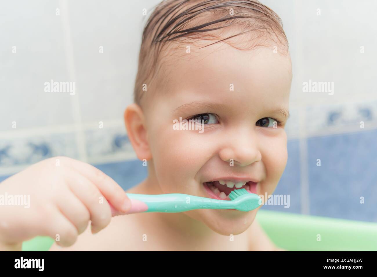 beautiful baby brushing his teeth with a toothbrush in the bathroom ...