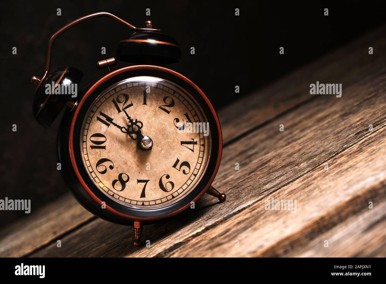 An old, vintage, retro alarm clock on a wooden table rolls off a ...