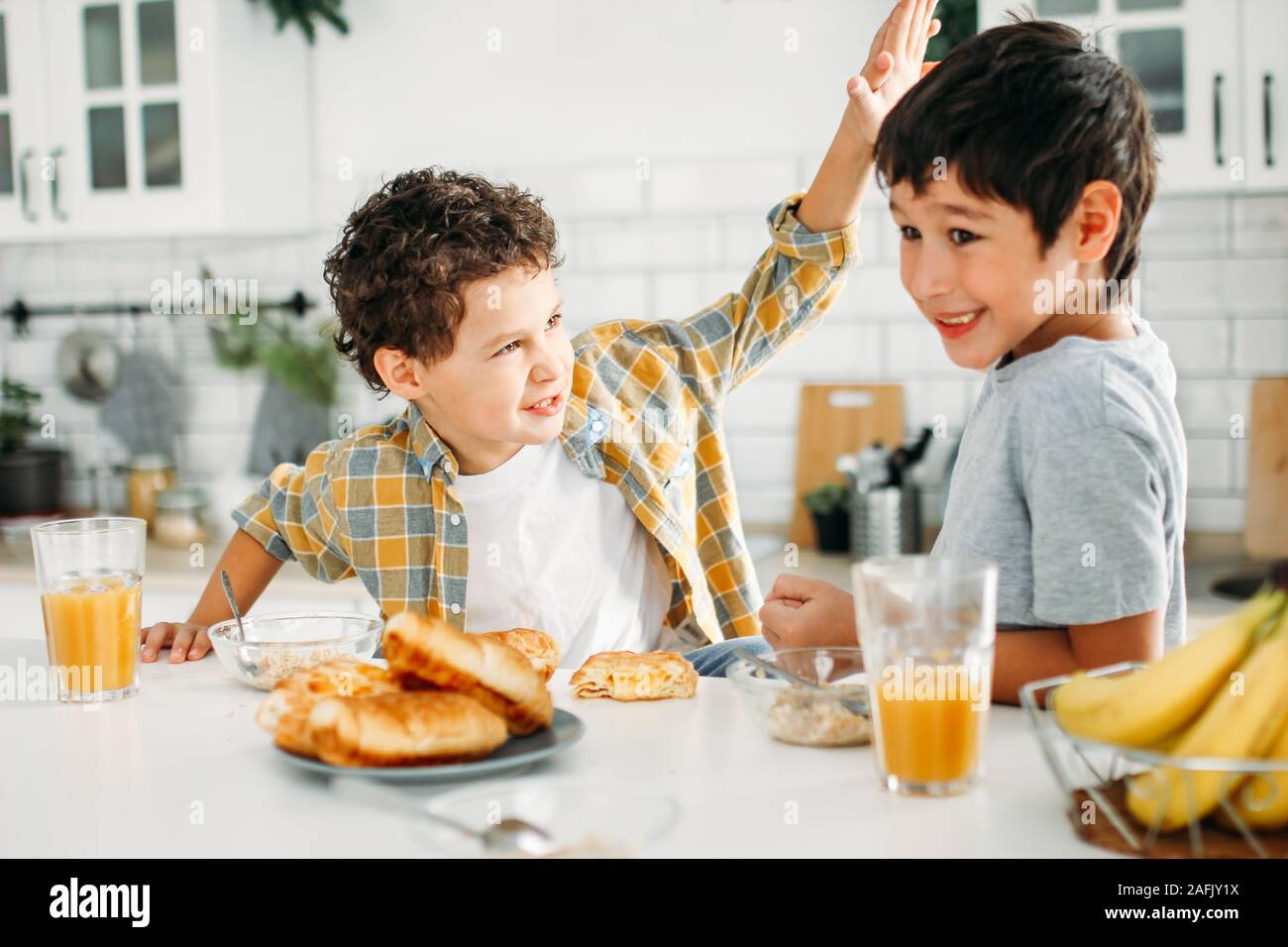 Two siblings tween boys brothers having breakfast on bright kitchen at ...