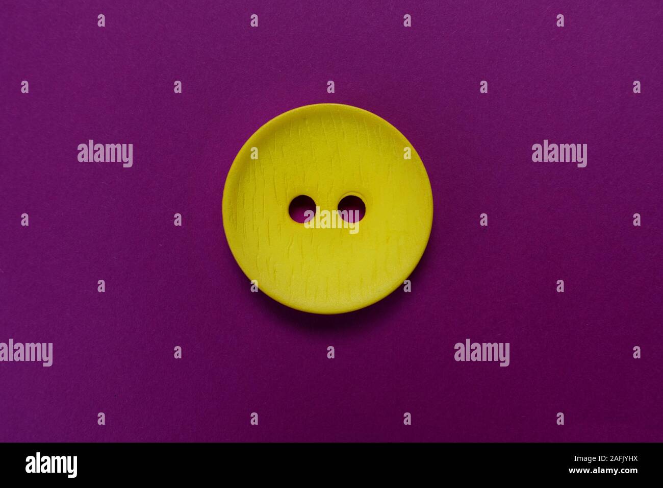 Big yellow button isolated on a purple background Stock Photo - Alamy