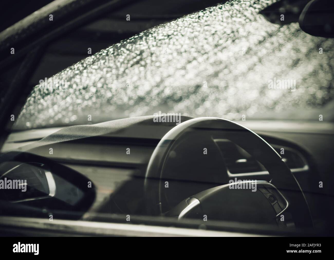 Black and white image of the car interior in rainy weather. There are a ...