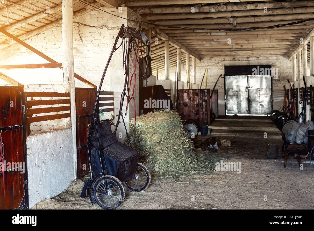 Old empty stables barn at horse farm with wooden beams , sulky cart and ...
