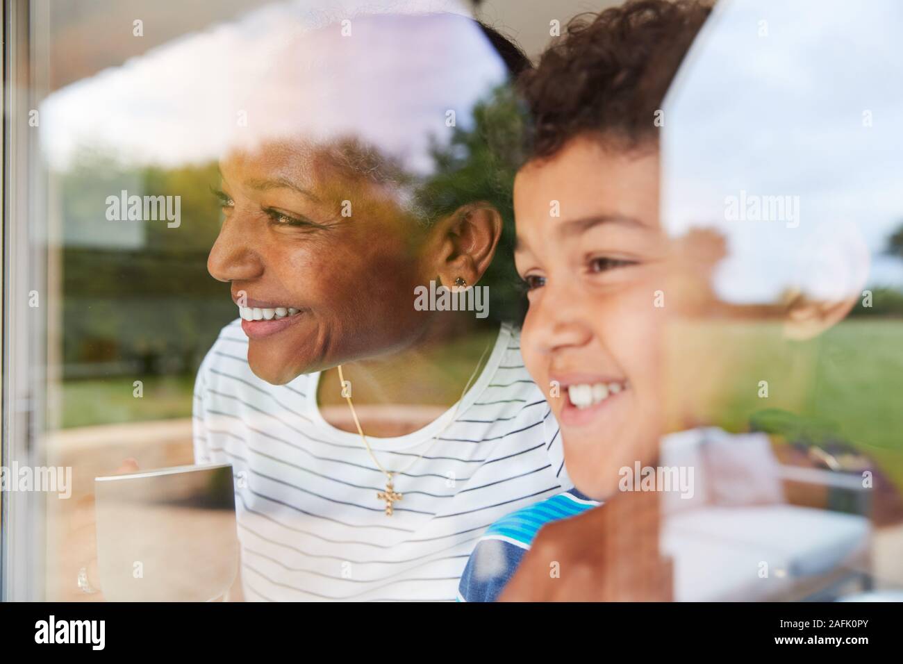 Grandmother With Grandson At Home Looking Out Through Window To Garden ...