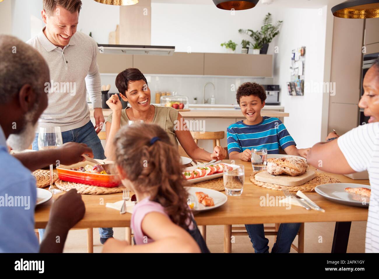 Father Serving As Multi-Generation Mixed Race Family Eat Meal Around ...