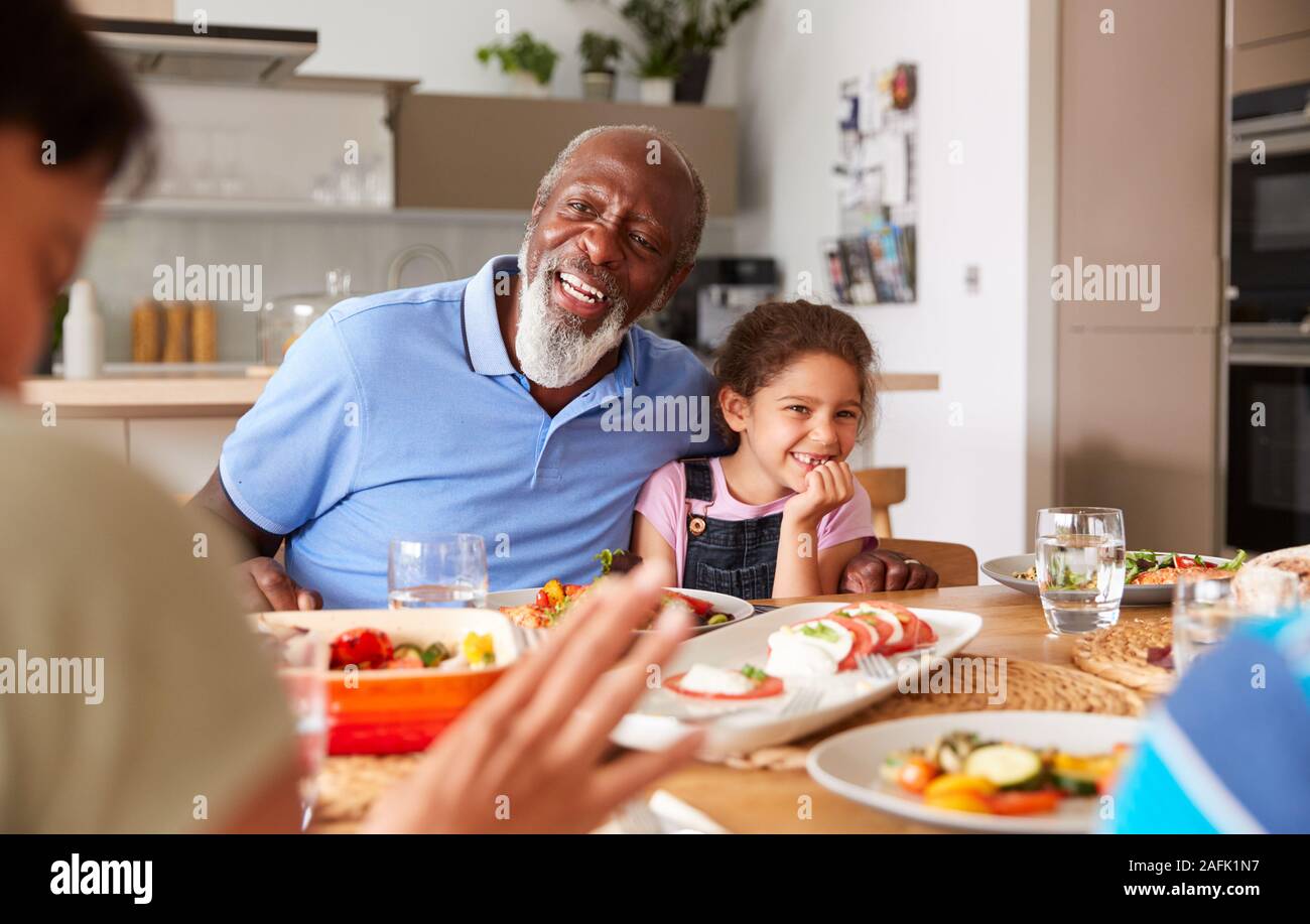 Multi-Generation Mixed Race Family Eating Meal Around Table At Home ...