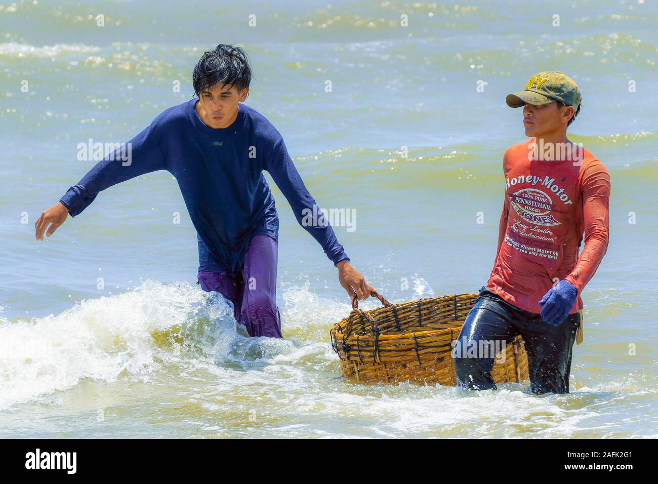 Fishermen drag a basket of smaller fish from their catch at this quiet ...