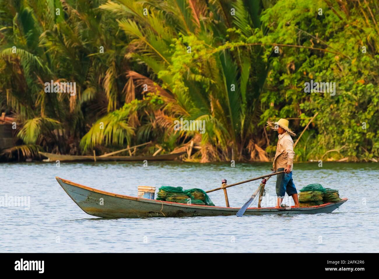 Fisherman with large straw hat rowing boat with nets on the Praek Tuek ...