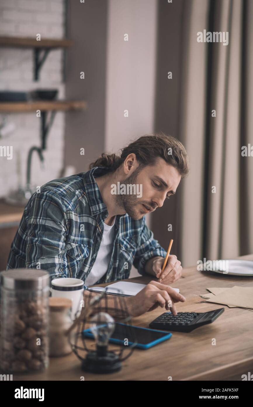 Long-haired man doing precise calculations for his business Stock Photo ...