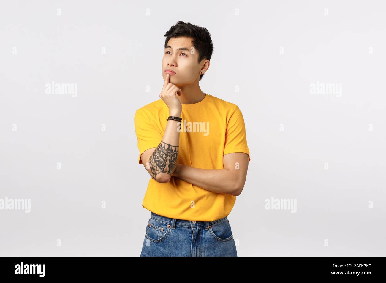 Thoughtful young handsome asian boyfriend with tattoos, standing in ...