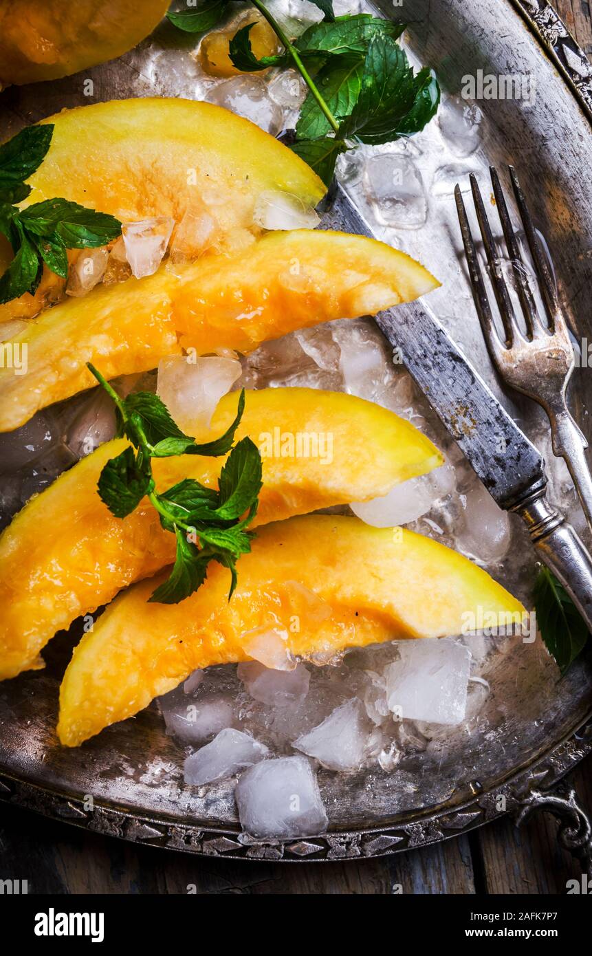 Top view of cantaloupe melon slices with mint and ice served on vintage ...