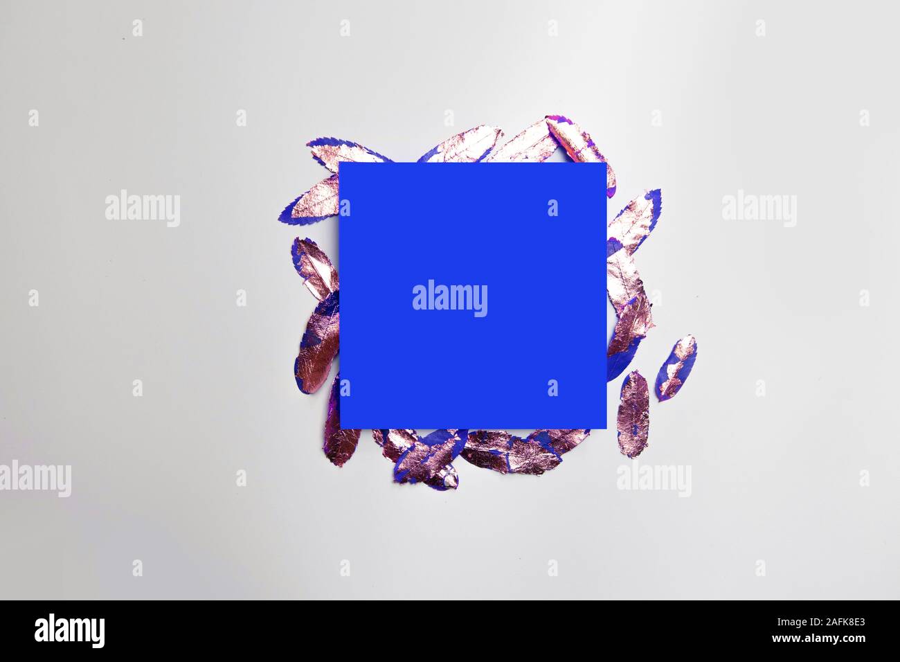 Top view composition of blue paper frame with gold leaves on a gray ...