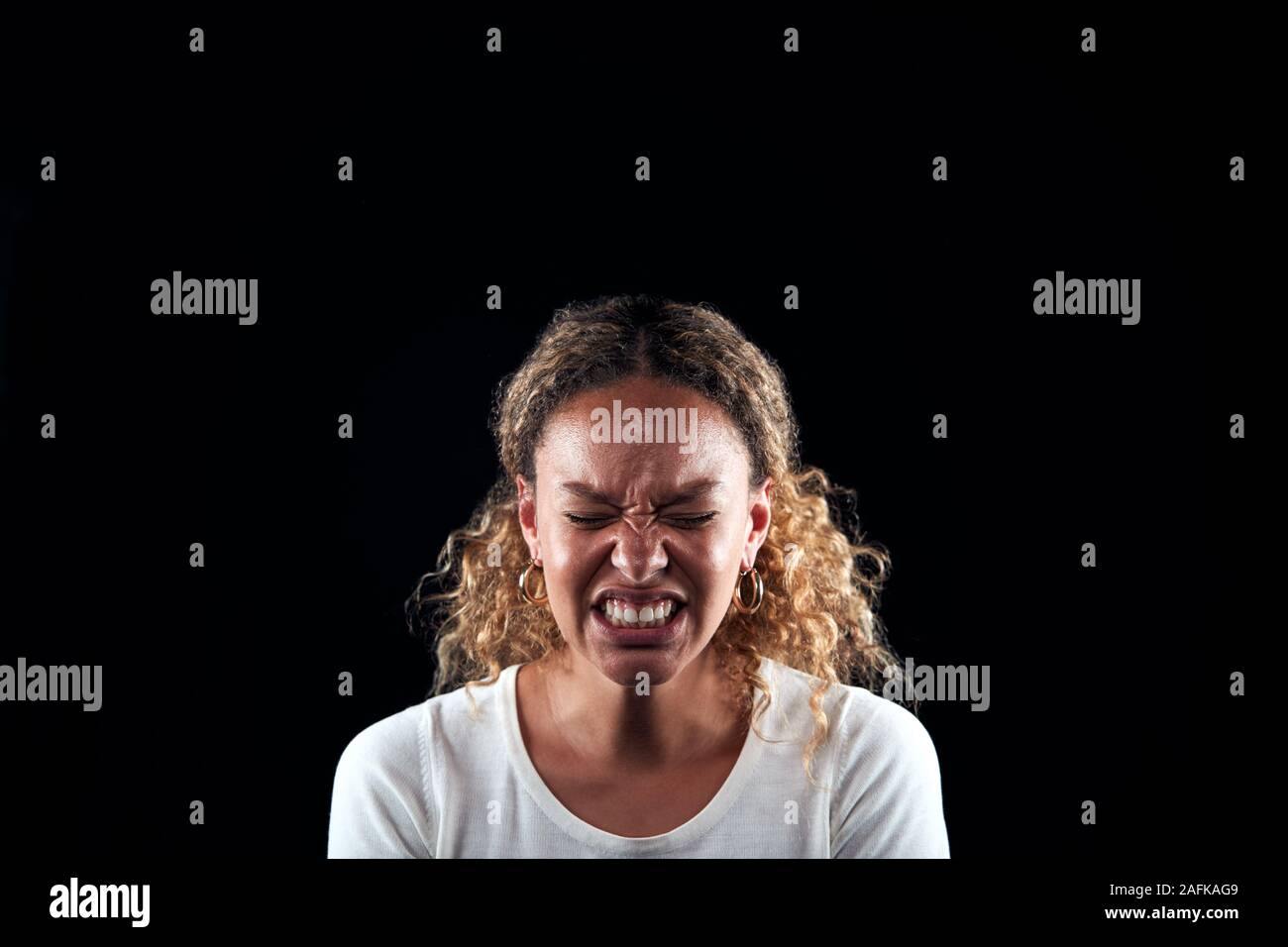 Studio Portrait Of Angry Woman Shouting At Camera Against Black ...