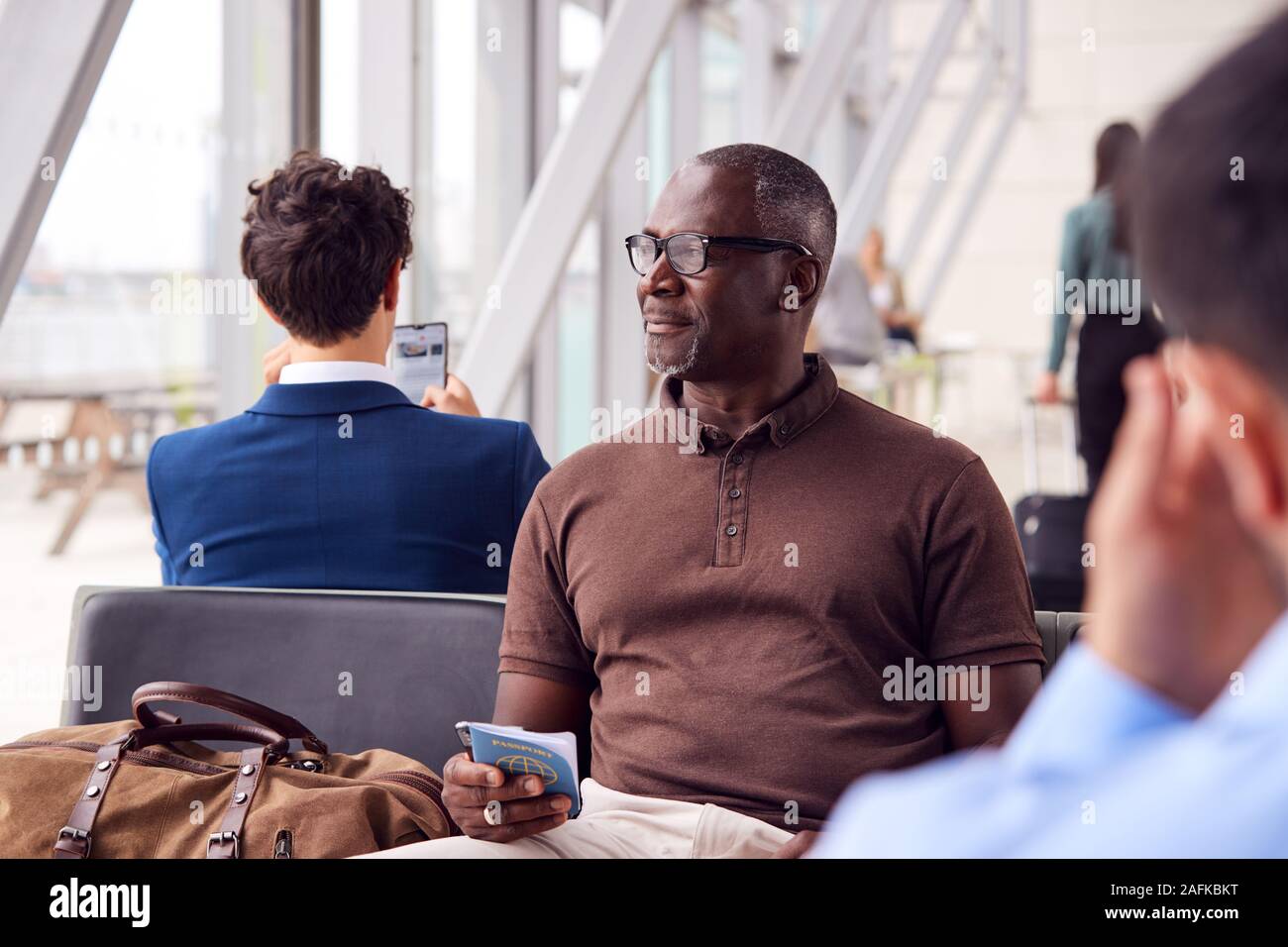 Male Passenger Sitting In Airport Departure Lounge Holding Passport ... Male Passenger Sitting In Airport Departure Lounge Holding Passport ...