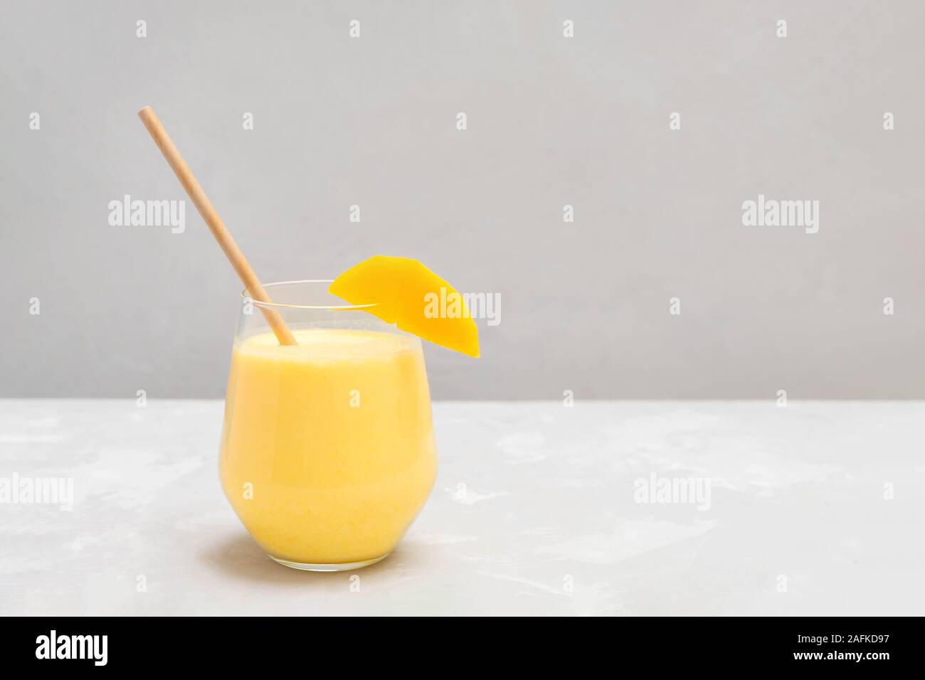 Traditional indian drink Mango Lassi in a glass cup with paper straw on ...