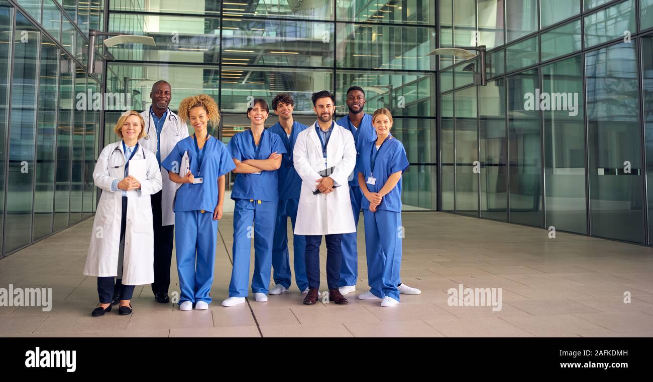 Portrait Of Smiling Medical Team Standing In Modern Hospital Building ...
