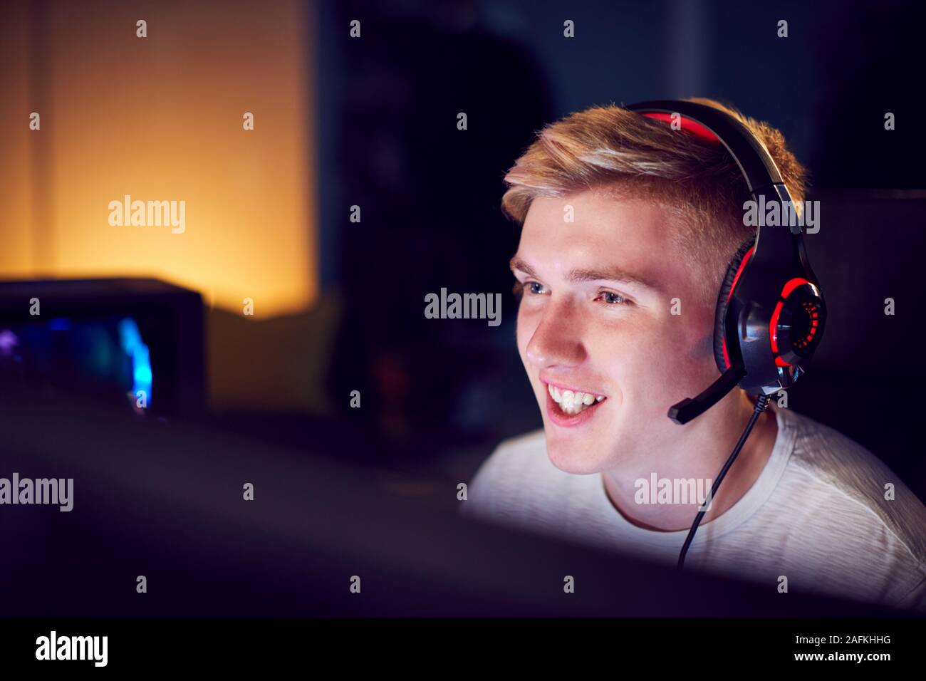 Teenage Boy Wearing Headset Gaming At Home Using Dual Computer Screens ...