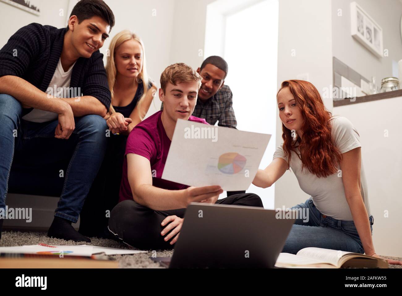 Group Of College Students In Lounge Of Shared House Studying Together ...