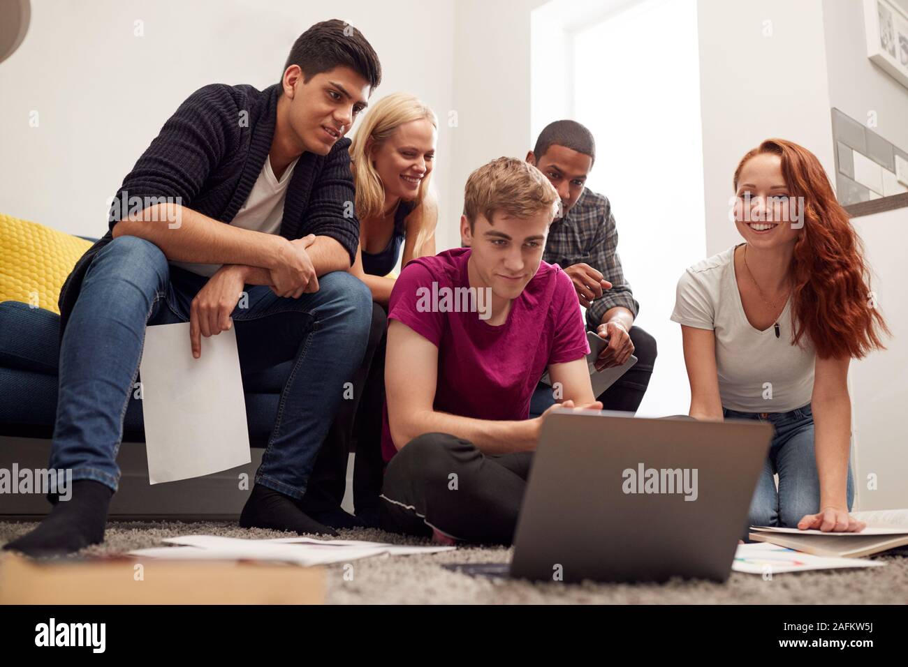 Group Of College Students In Lounge Of Shared House Studying Together ...